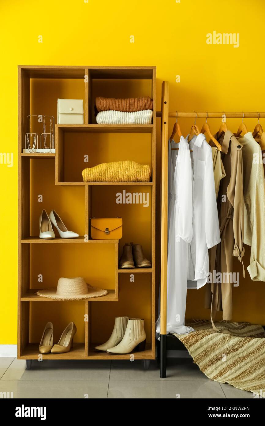 Interior of stylish dressing room with rack, clothes and shelving unit ...
