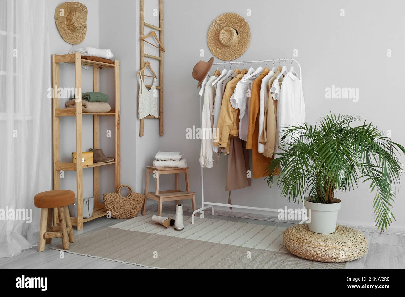 Interior of light dressing room with rack, clothes and shelving unit ...