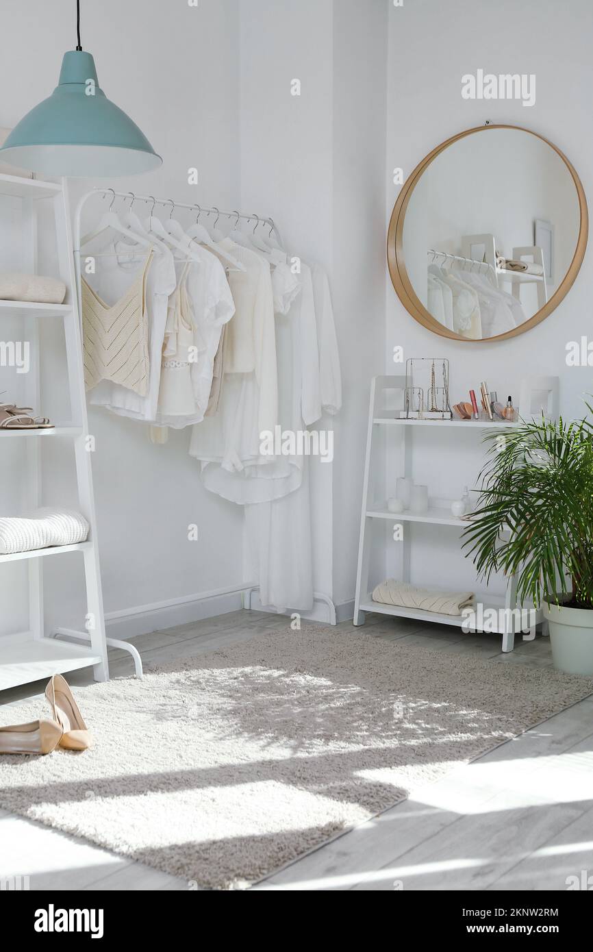 Interior of light dressing room with rack, clothes and shelving units ...