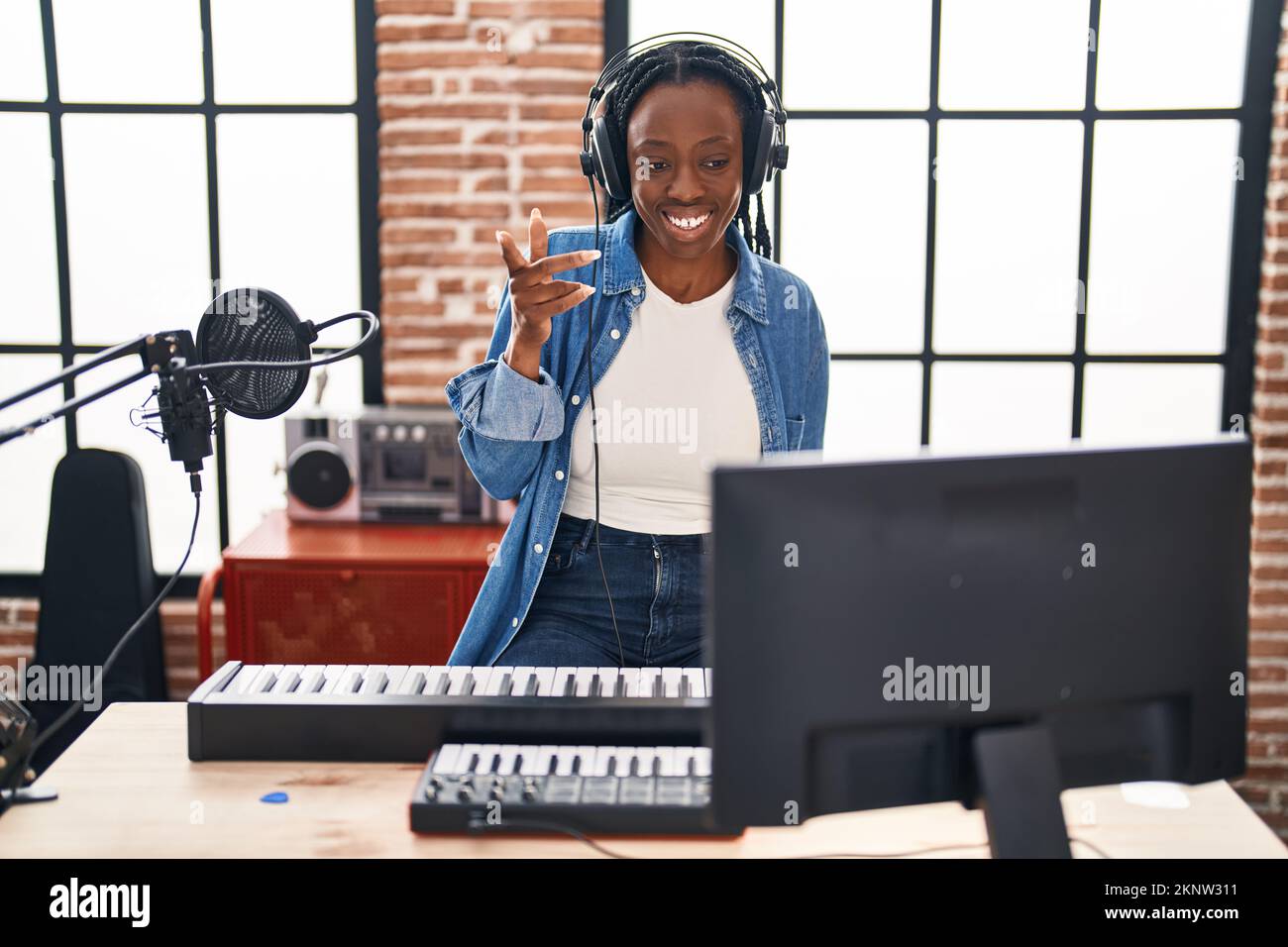 Beautiful black woman playing piano at music studio smiling happy ...