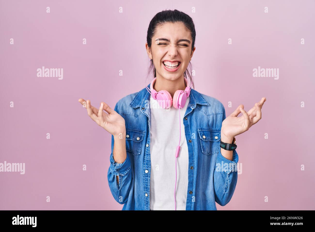 Young beautiful woman standing over pink background celebrating mad and ...