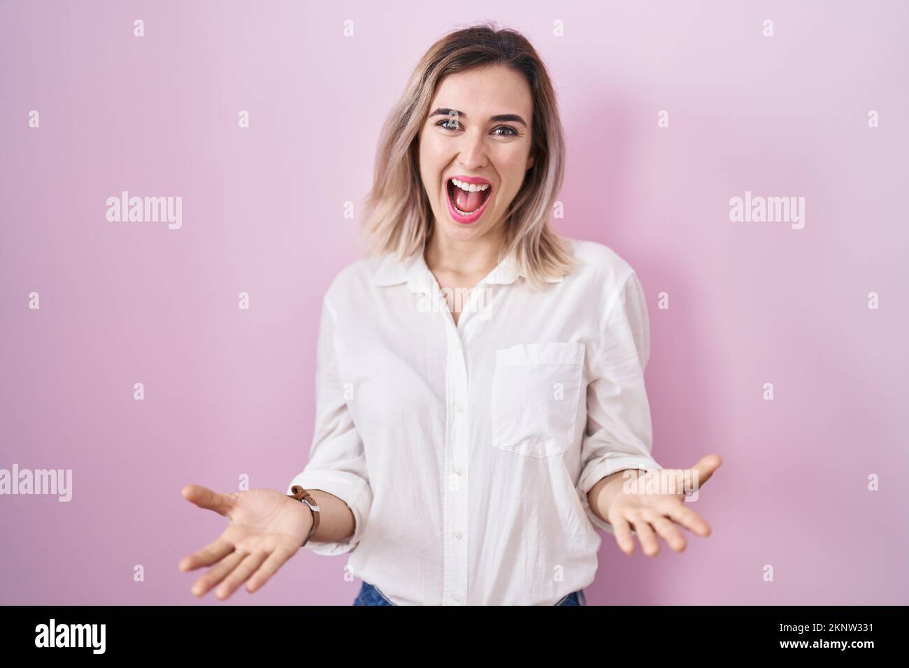 Young beautiful woman standing over pink background smiling cheerful ...