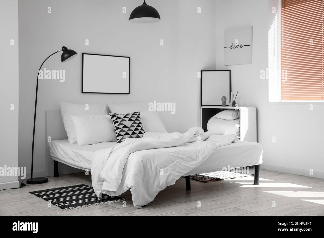 Interior of light bedroom with lamp, shelving unit and blank frames ...