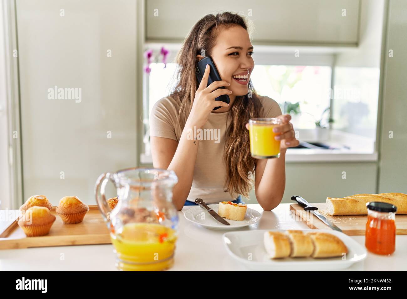 Young beautiful hispanic woman having breakfast talking on smartphone ...