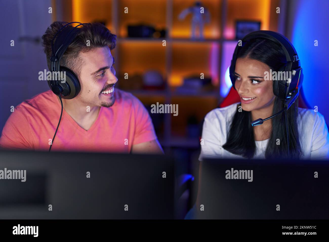 Man and woman streamers playing video game using computer at gaming ...
