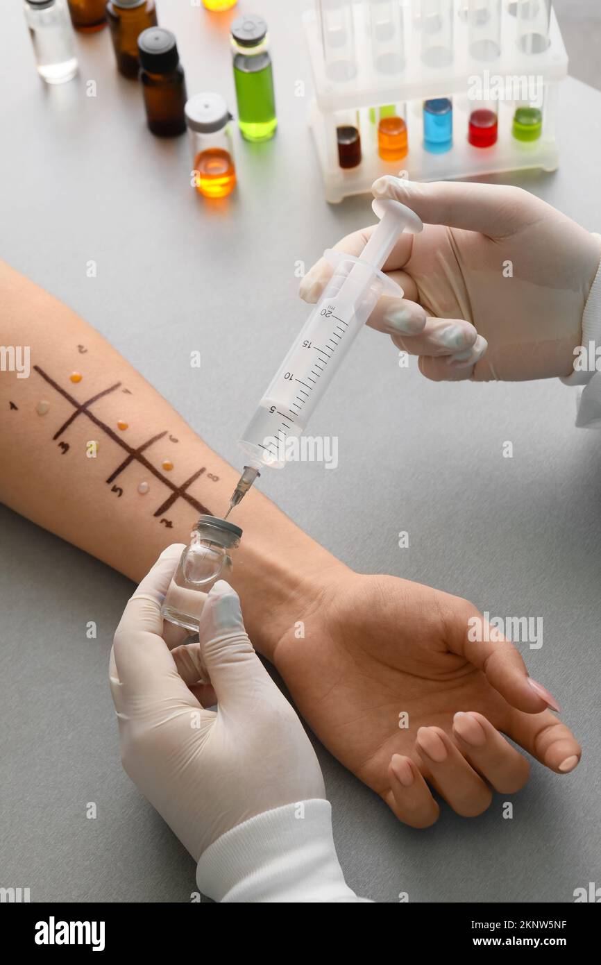 Doctor with syringe and ampule making allergy skin test to patient in ...