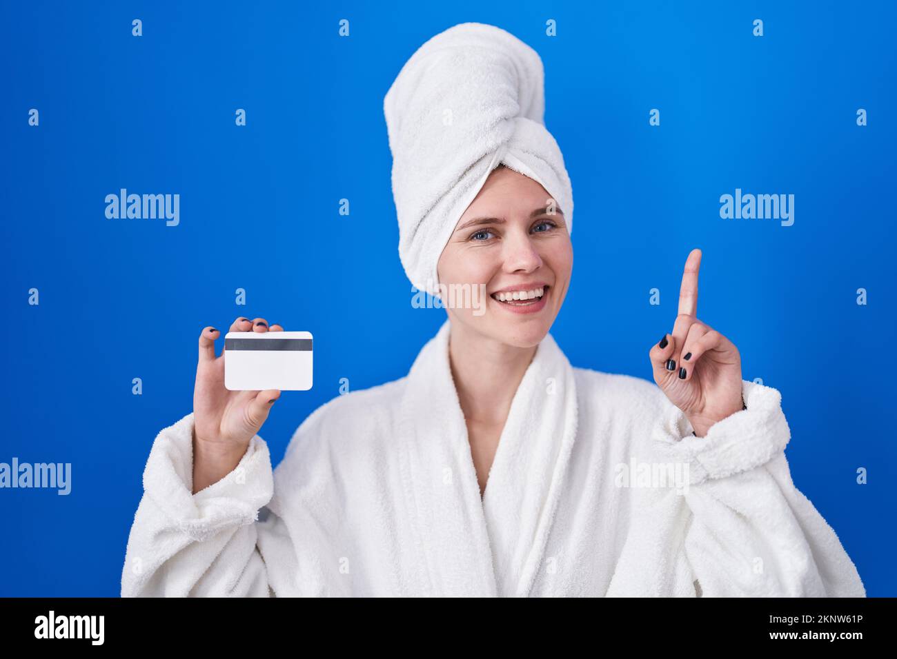 Blonde caucasian woman wearing bathrobe holding credit card surprised ...