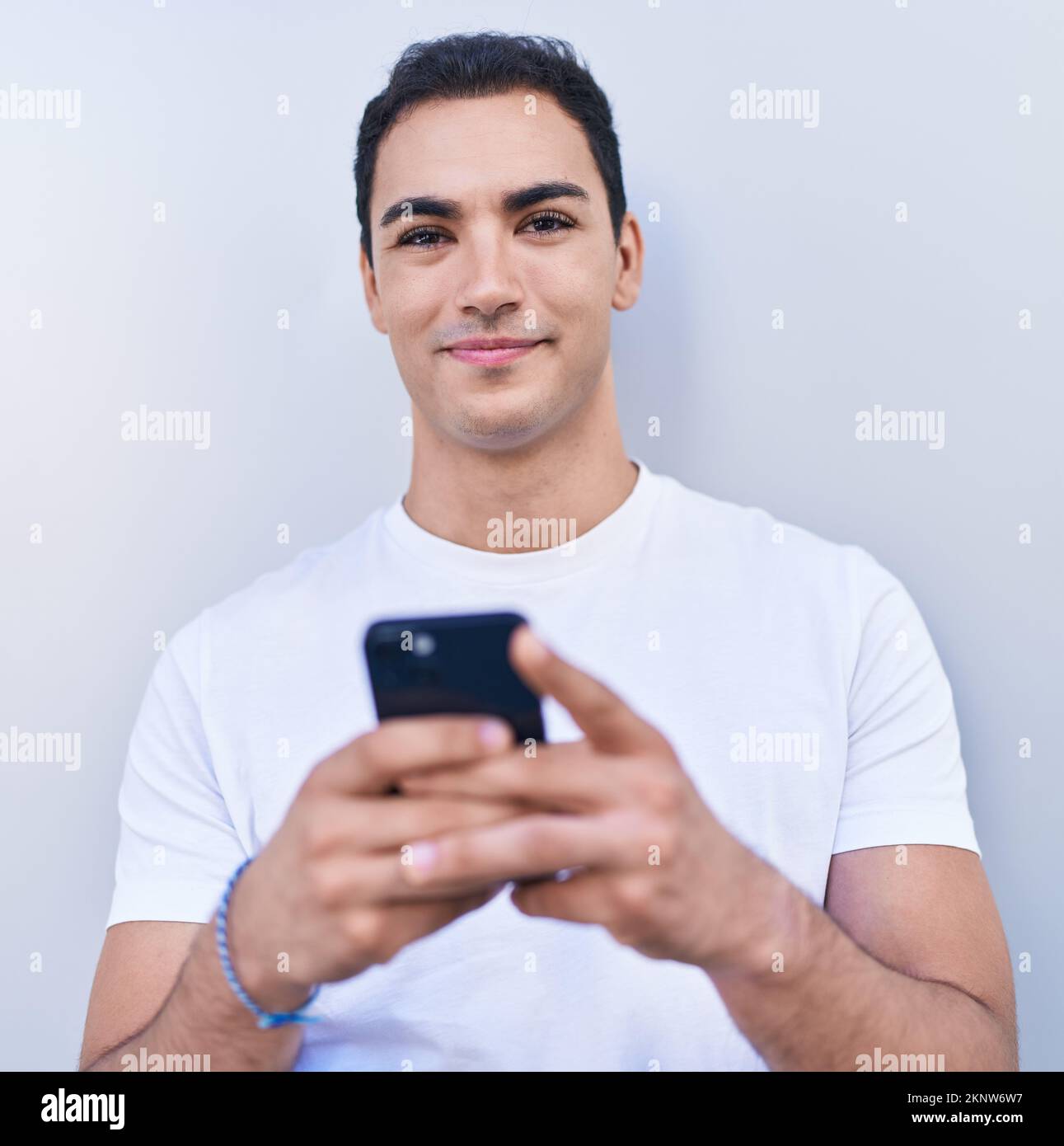 Young hispanic man smiling confident using smartphone over isolated ...