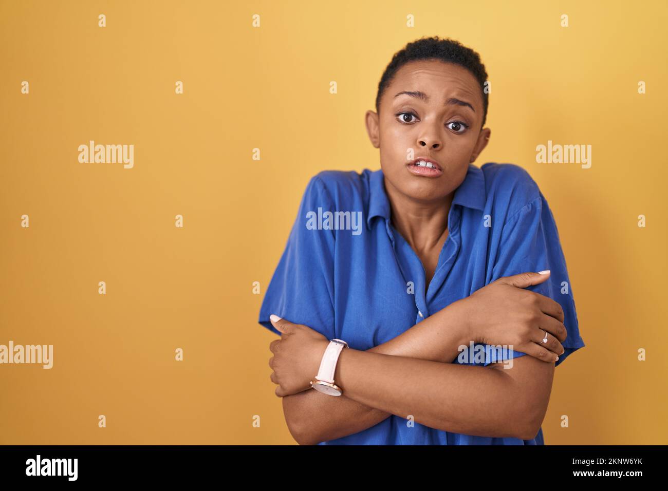 African american woman standing over yellow background shaking and ...