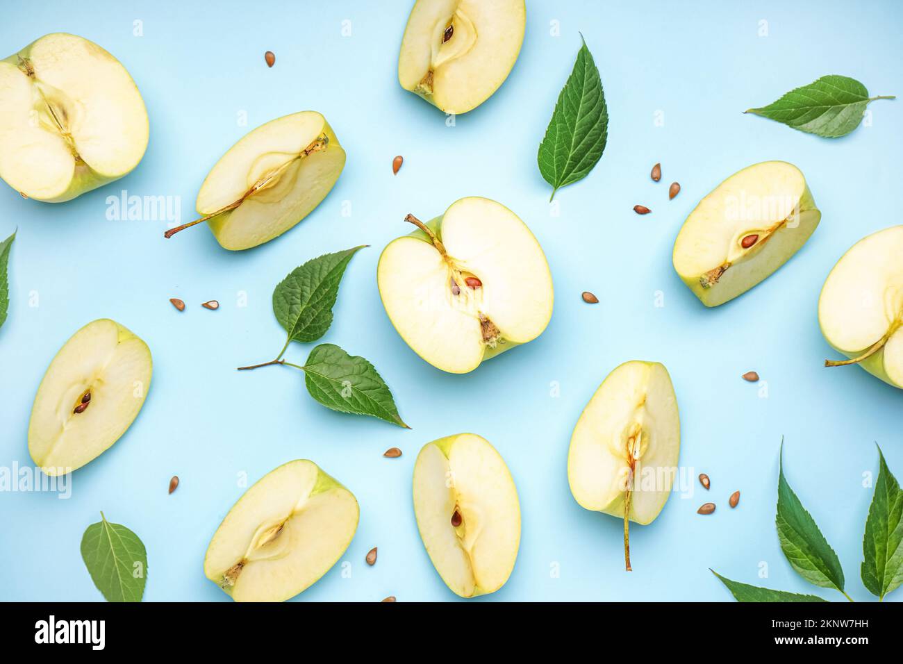 Pieces of juicy green apples, seeds and leaves on color background ...