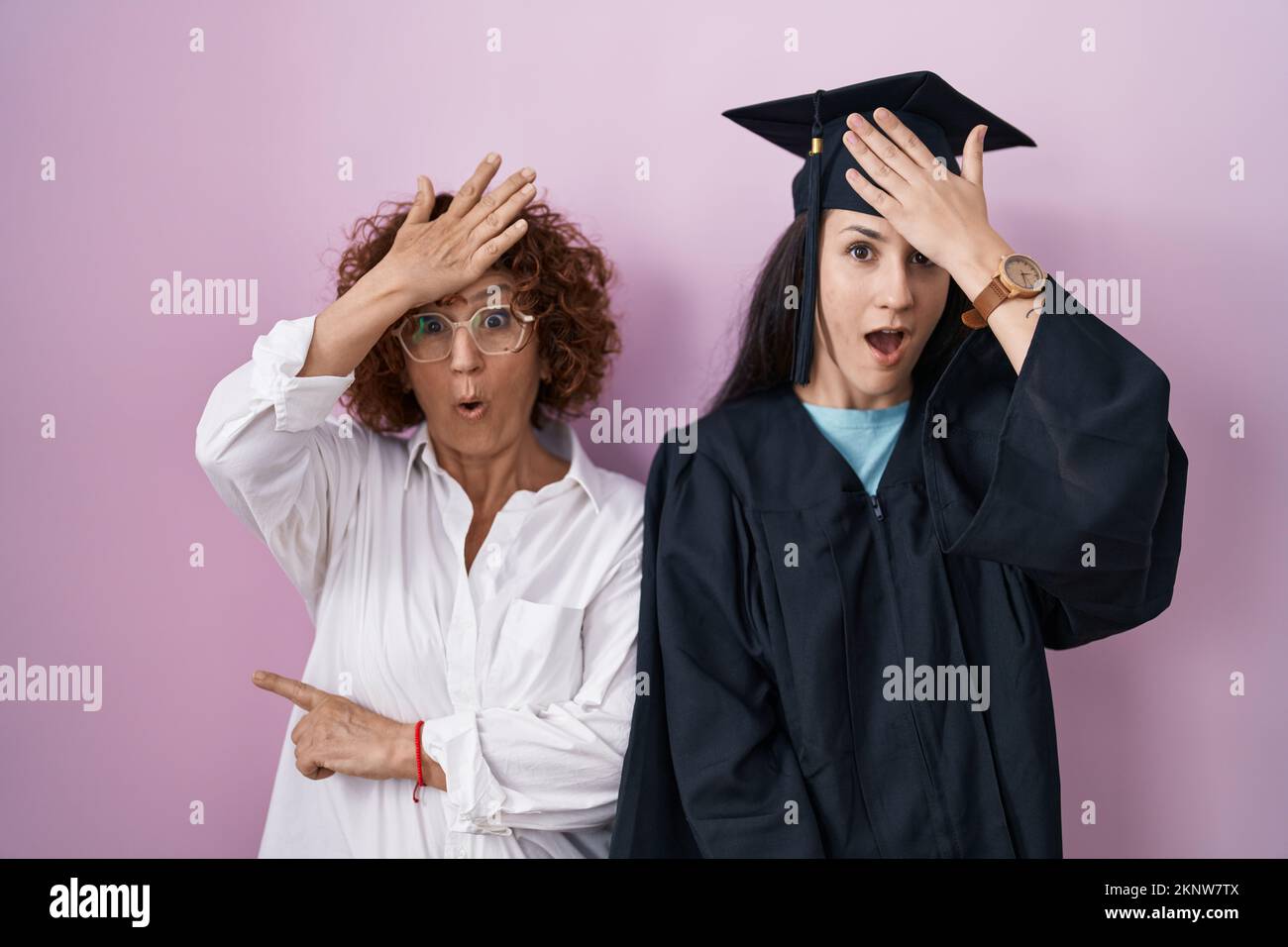 Hispanic mother and daughter wearing graduation cap and ceremony robe ...