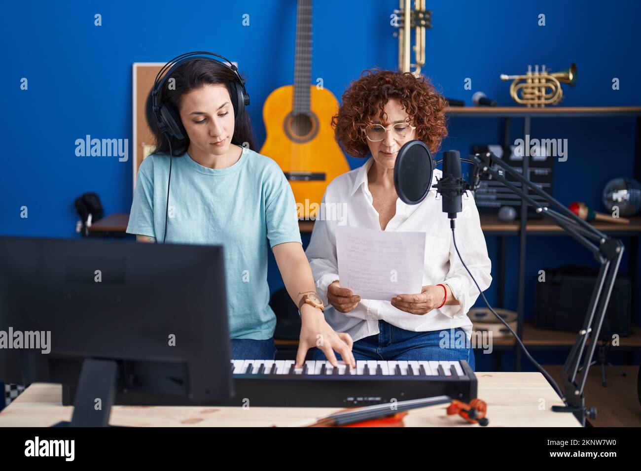Two women musicians singing song playing piano keyboard at music studio ...