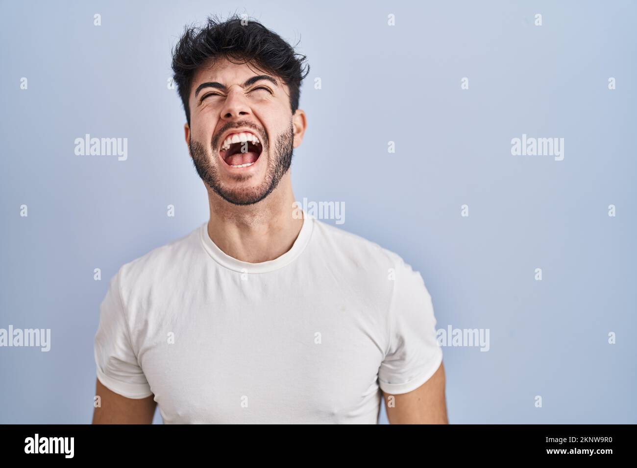 Hispanic man with beard standing over white background angry and mad ...