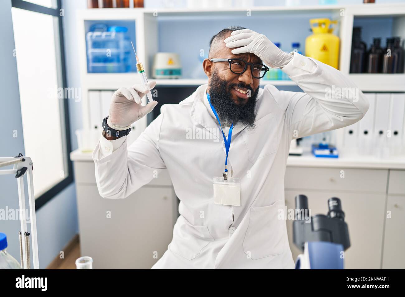 African american man working at scientist laboratory holding syringe stressed and frustrated ...