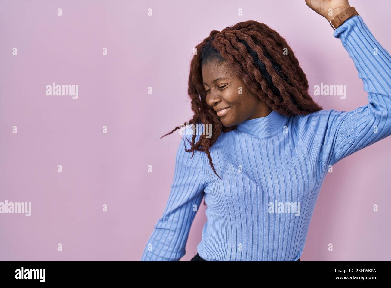 African woman standing over pink background dancing happy and cheerful ...