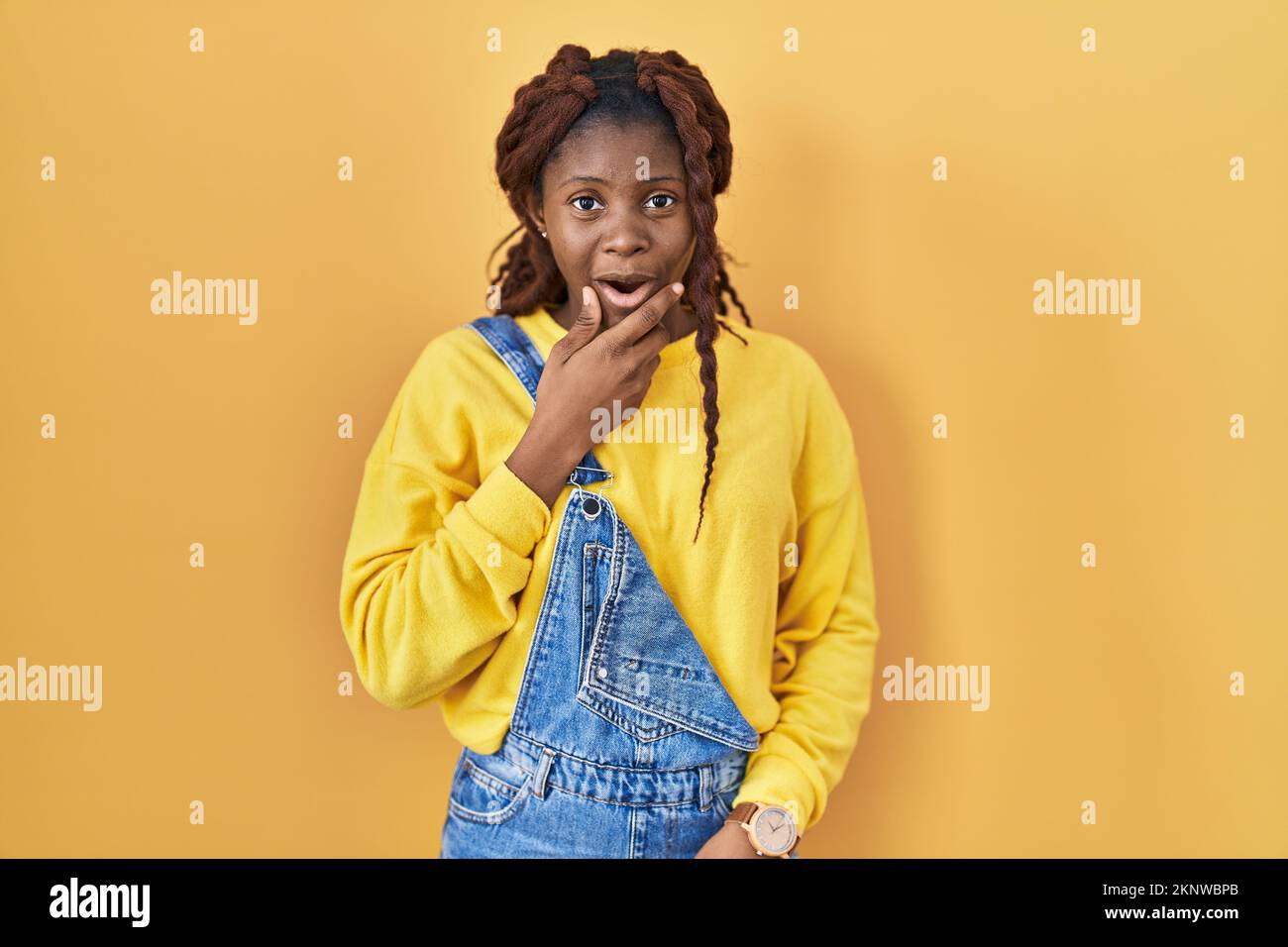 African woman standing over yellow background looking fascinated with ...