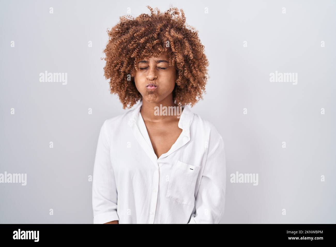 Young hispanic woman with curly hair standing over white background ...