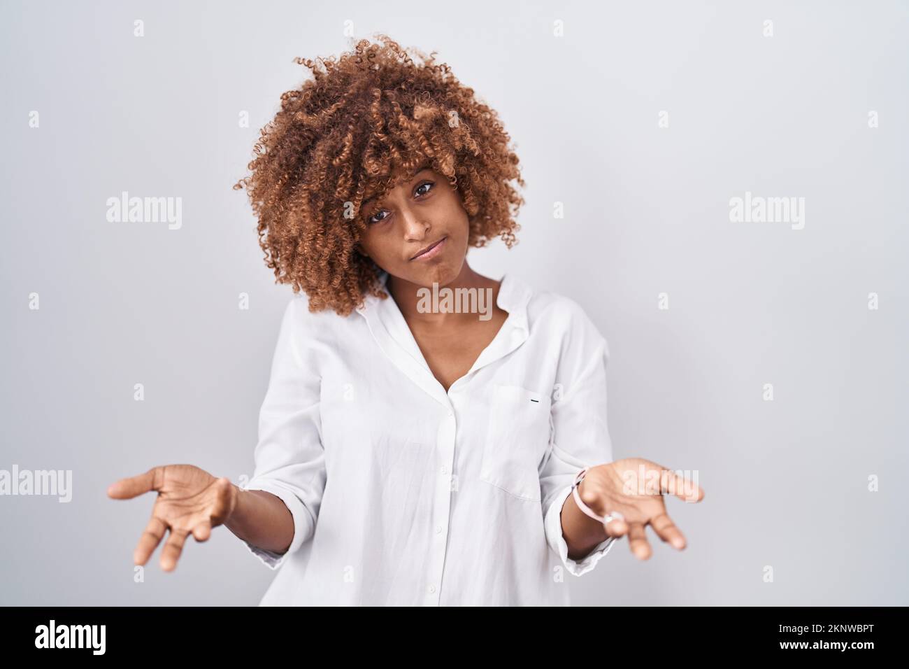 Young hispanic woman with curly hair standing over white background ...