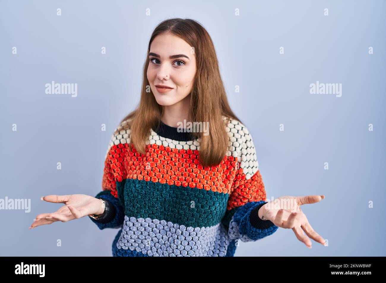 Young hispanic girl standing over blue background clueless and confused ...