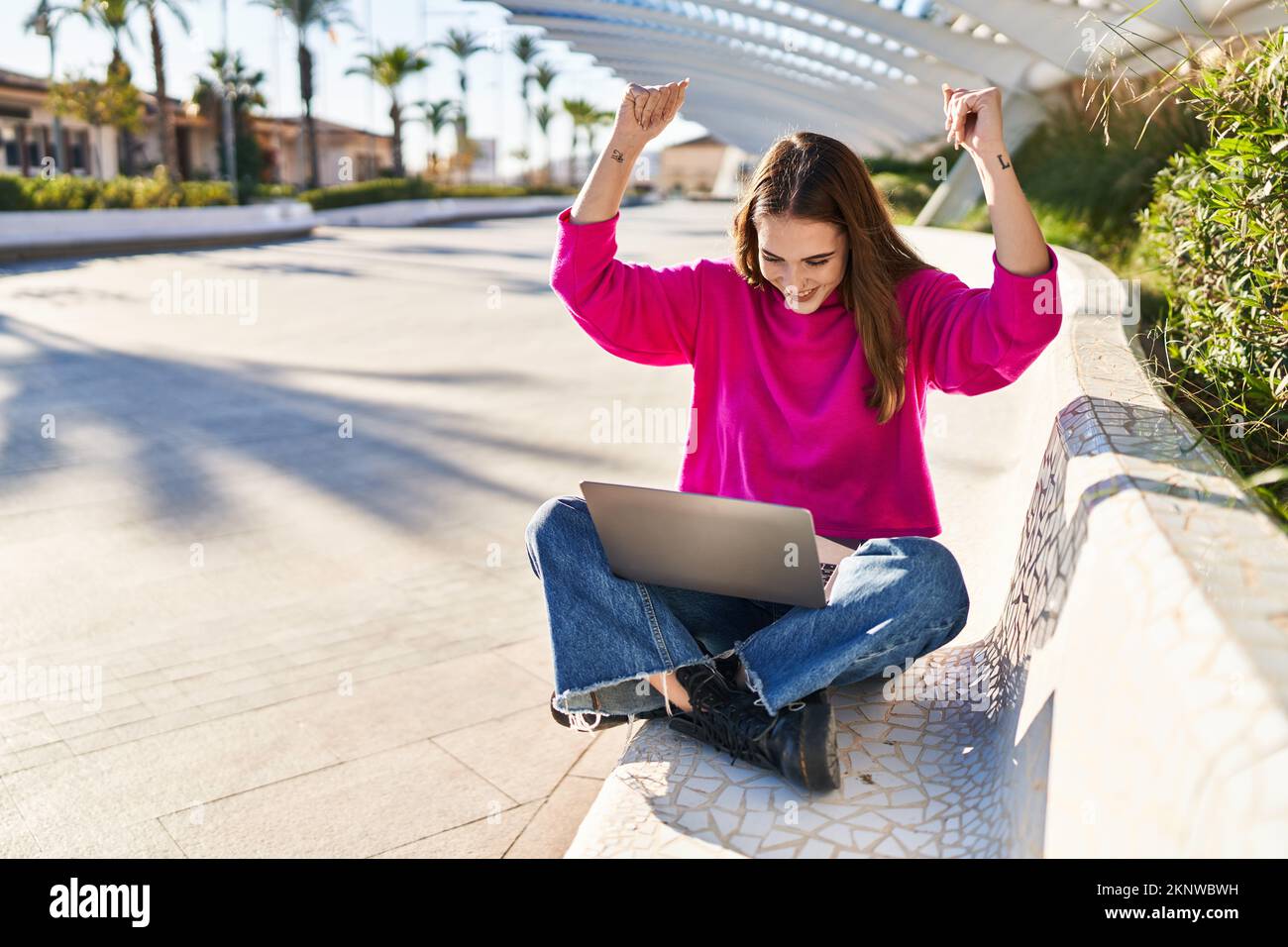 Young woman using laptop sitting on bench at park Stock Photo - Alamy