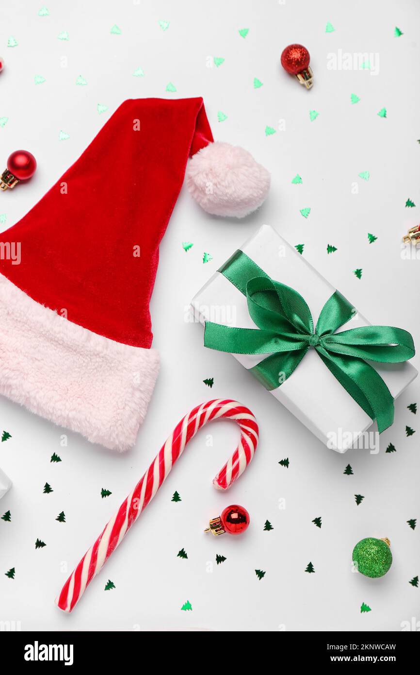 Composition with Christmas gift, balls, candy cane and Santa hat on ...