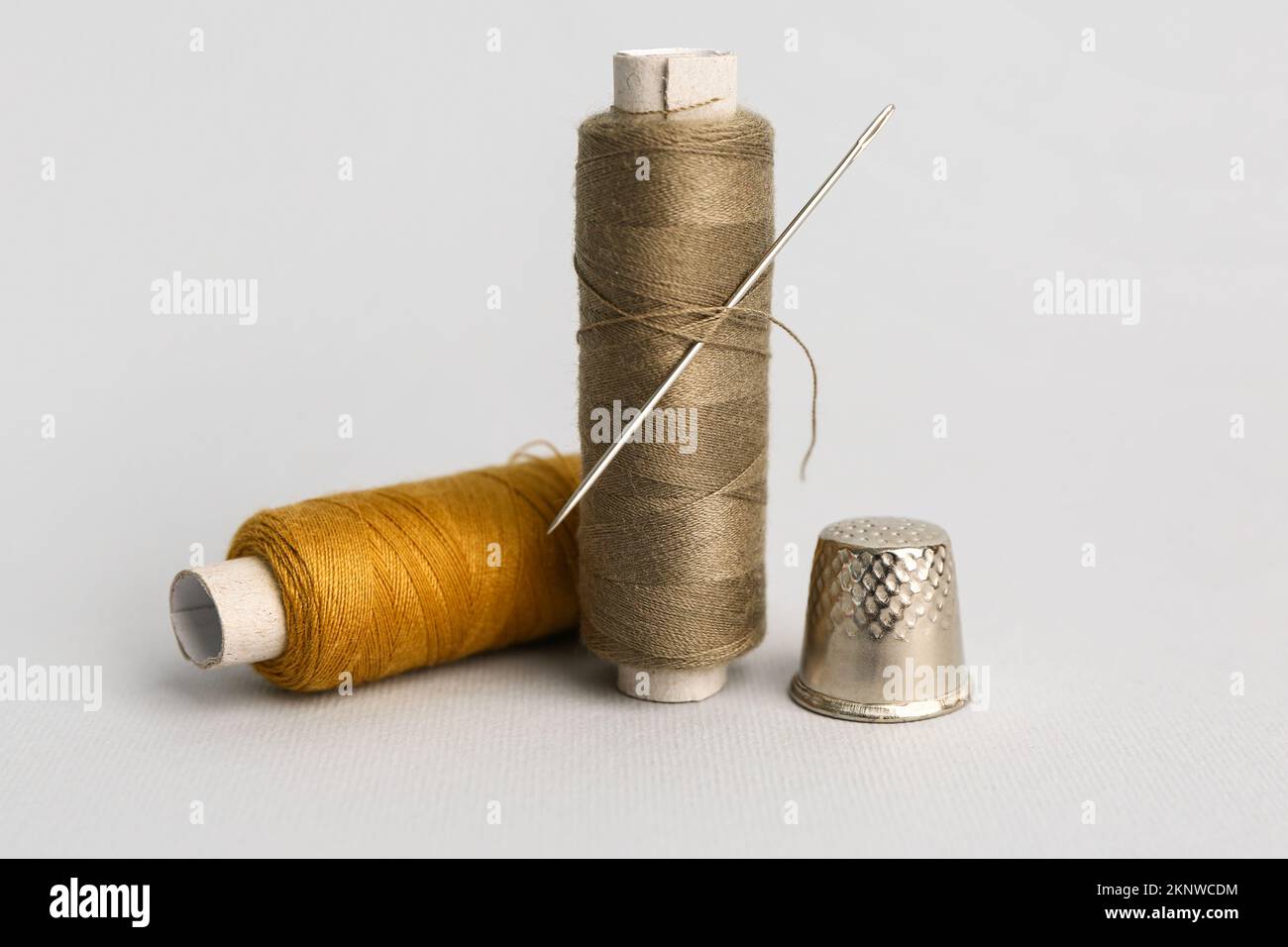 Thread spools with needle and thimble on grey background Stock Photo ...
