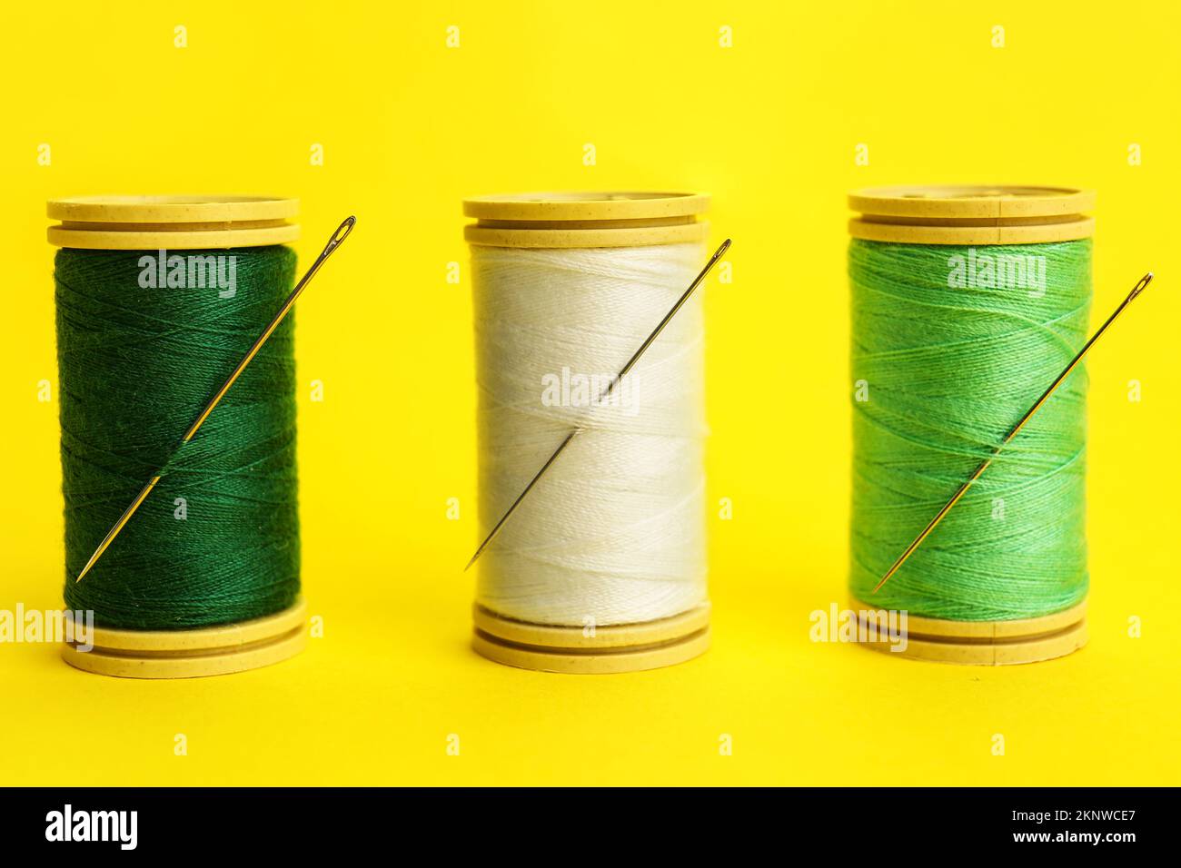 Thread spools with needles on yellow background, closeup Stock Photo ...