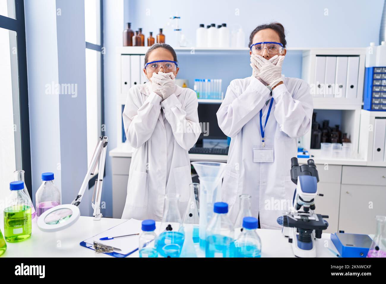 Young mother and daughter at scientist laboratory shocked covering ...
