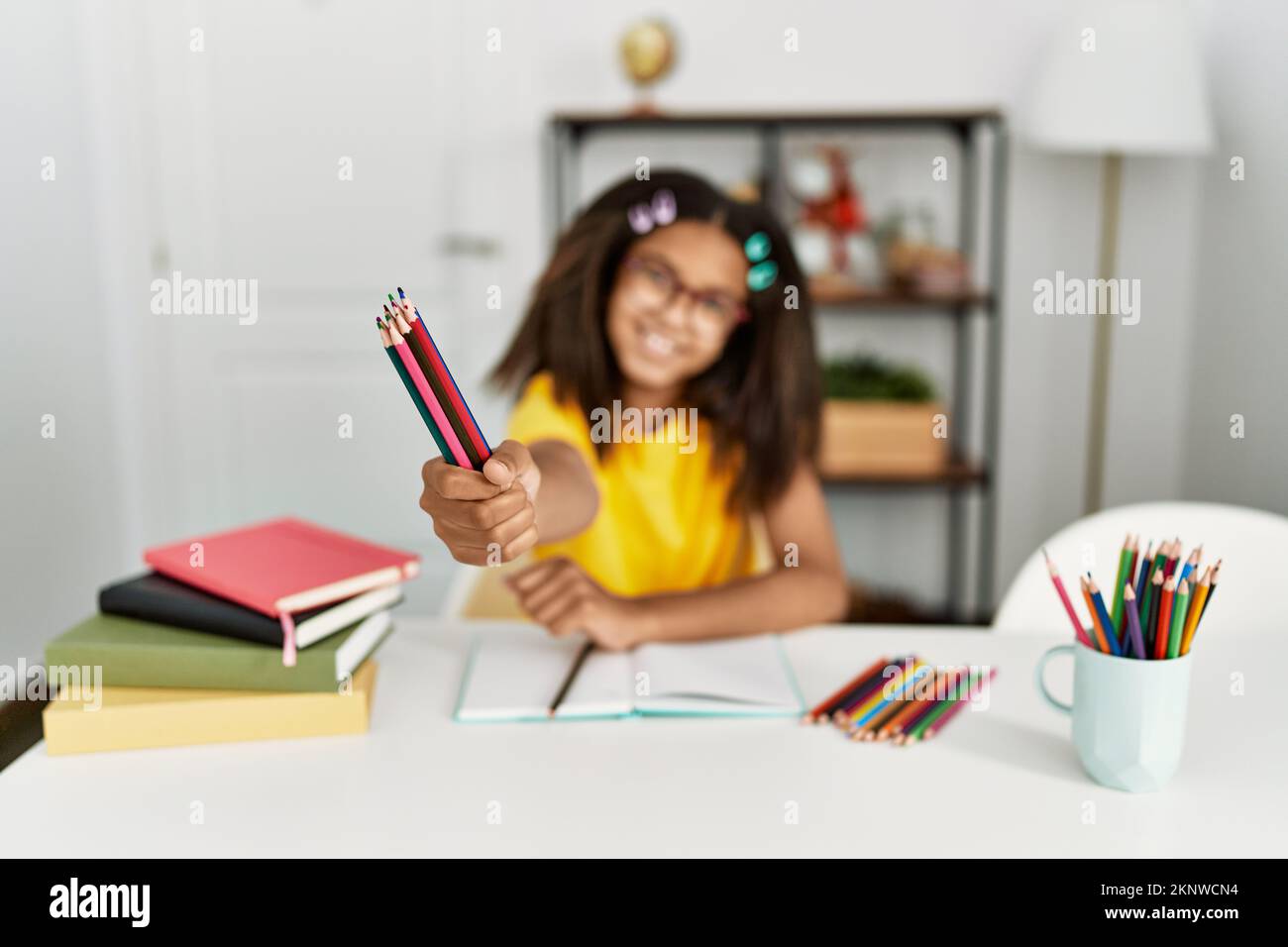 African american girl doing school homework holding pencils at home ...