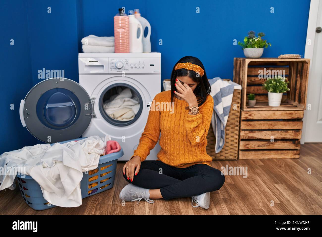 Young hispanic woman doing laundry tired rubbing nose and eyes feeling ...