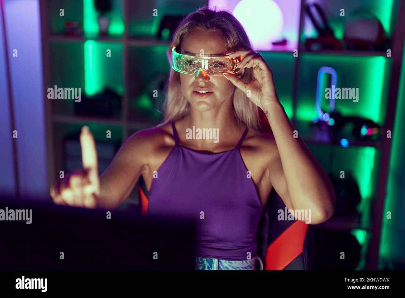 Young blonde woman streamer playing video game using virtual reality ...