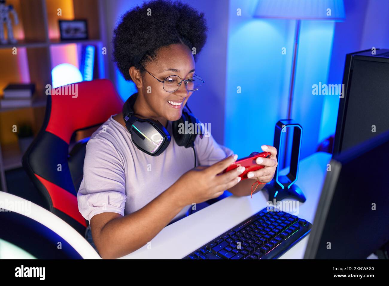 African american woman streamer using smartphone playing video game at ...