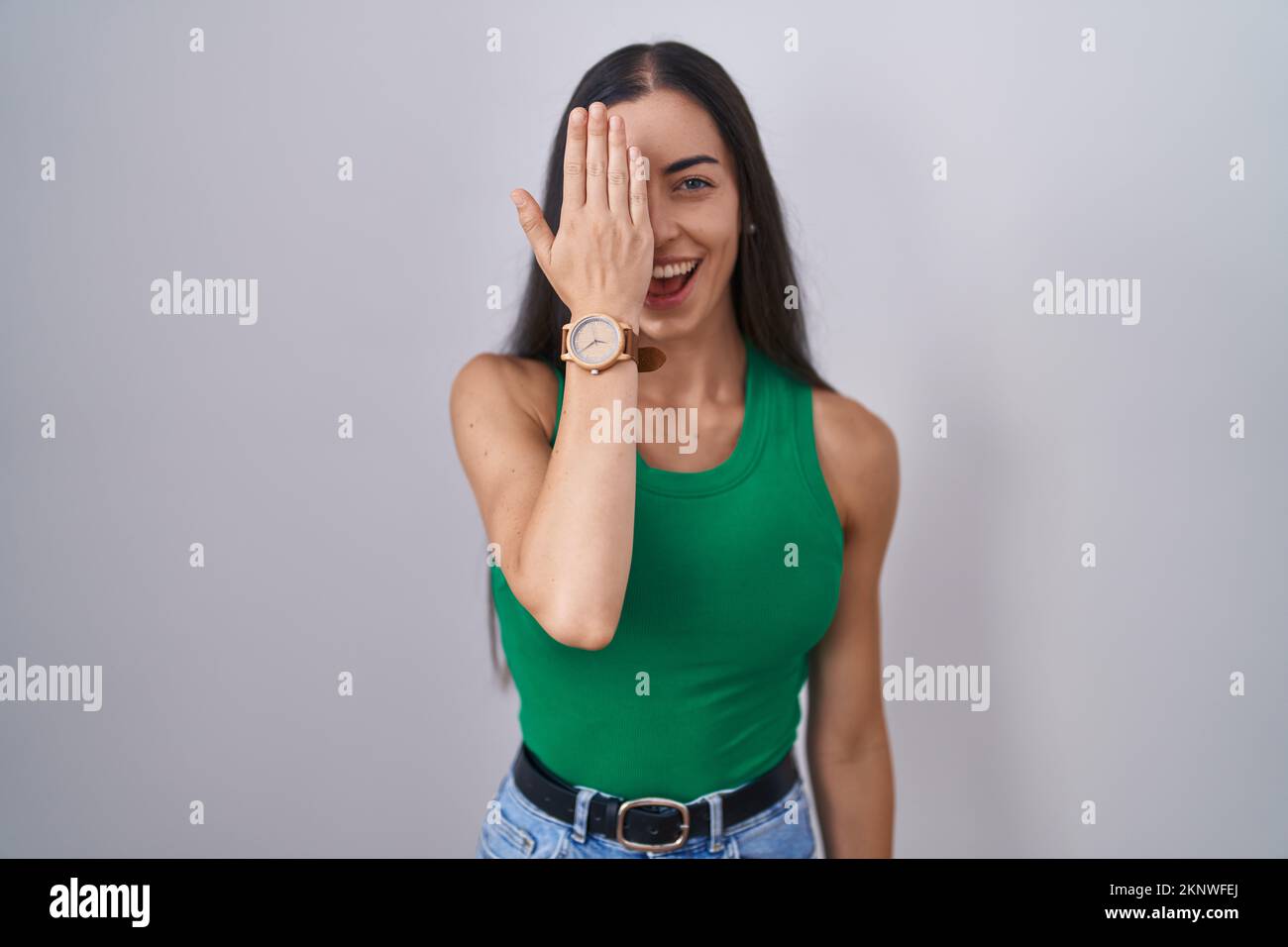 Young woman standing over isolated background covering one eye with ...