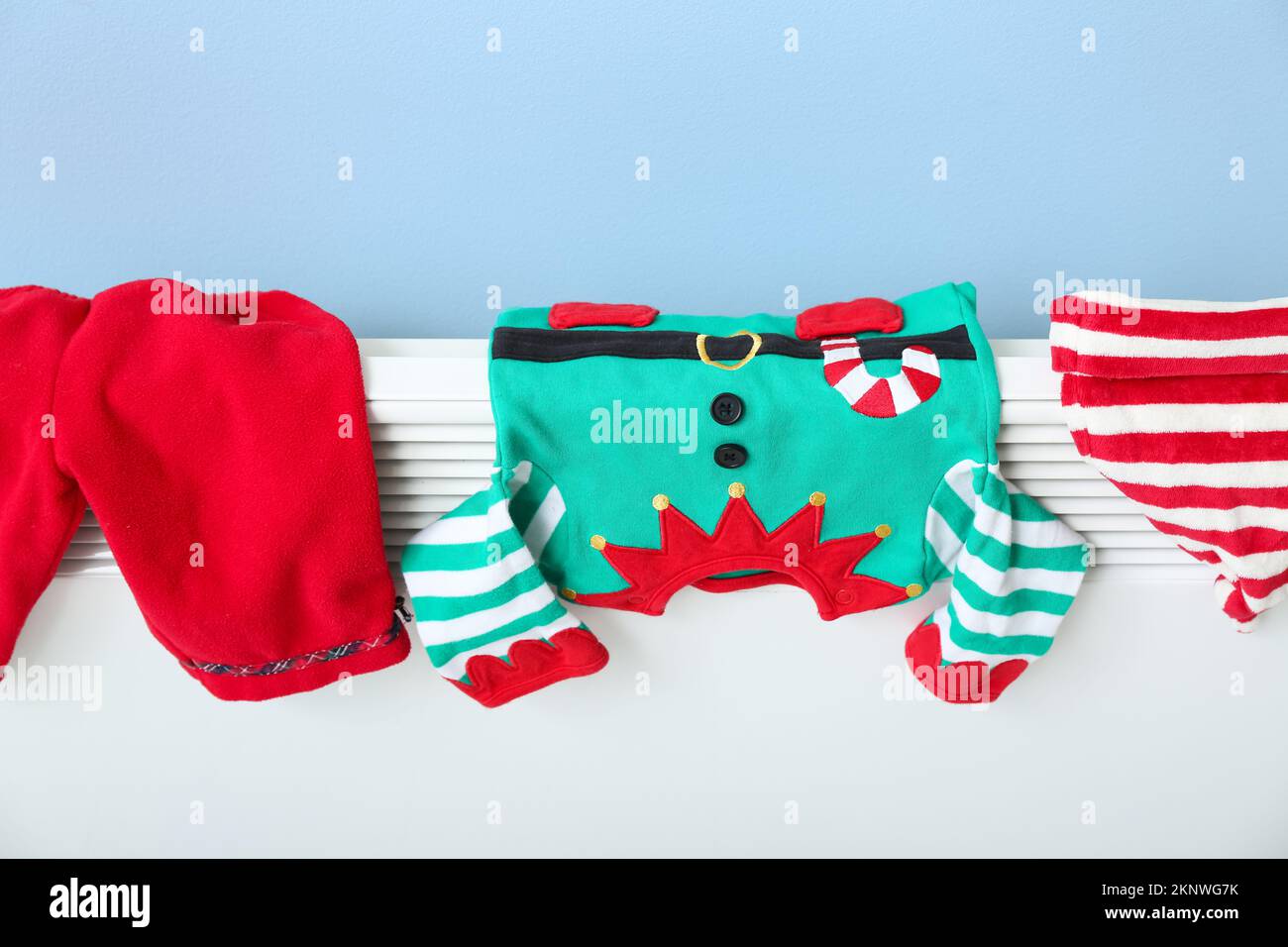 Baby elf costume drying on electric radiator near light wall, closeup ...