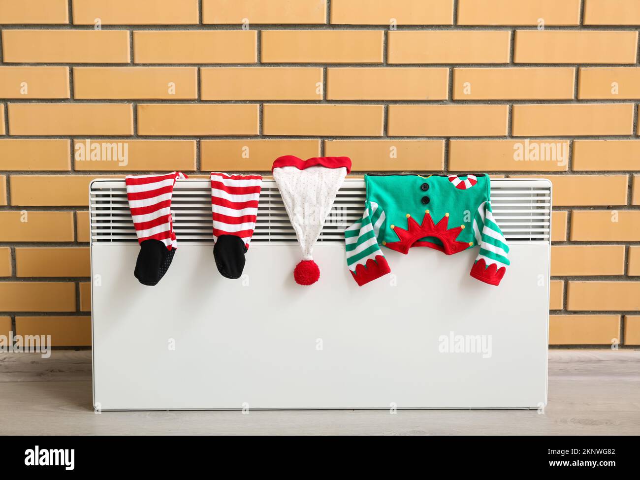 Baby elf costume drying on electric radiator near brick wall Stock ...
