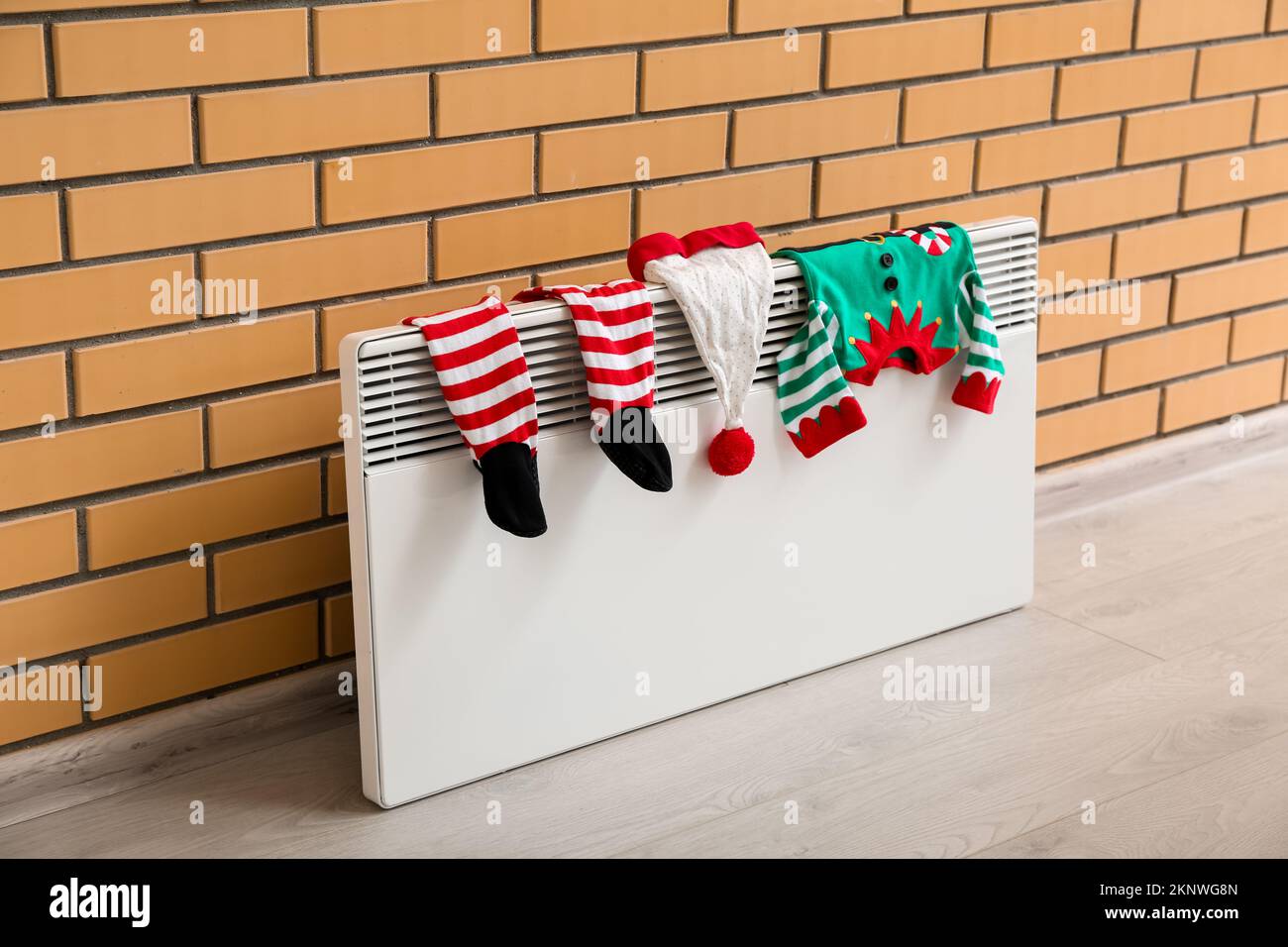 Baby elf costume drying on electric radiator near brick wall Stock ...