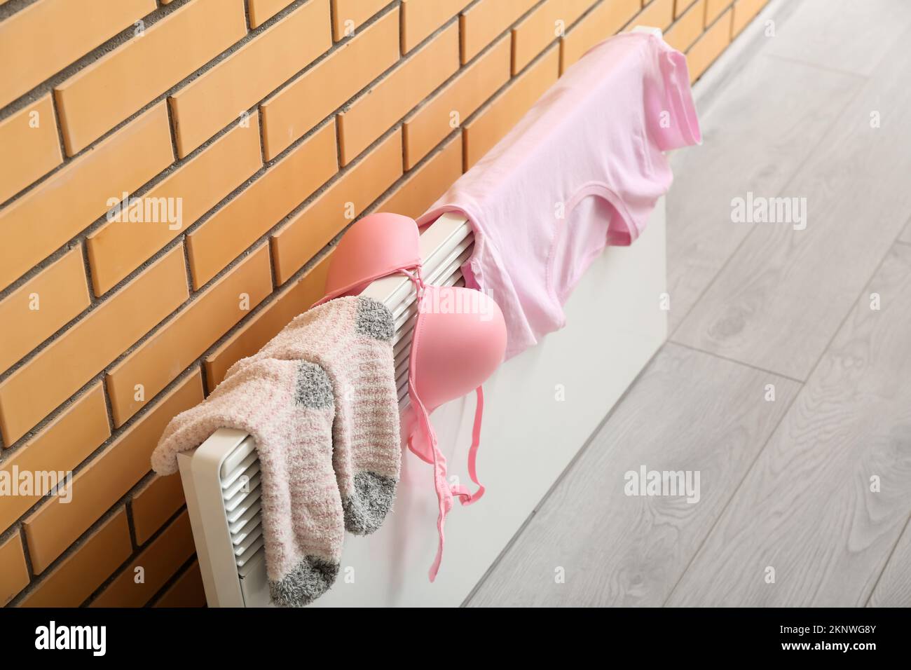 Female clothes drying on electric radiator near brick wall Stock Photo ...