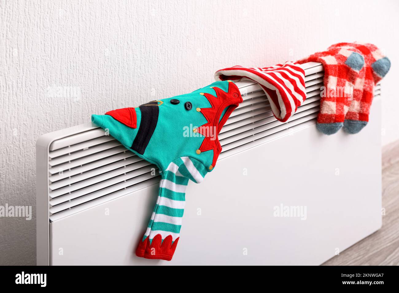 Baby elf costume and socks drying on electric radiator near light wall ...