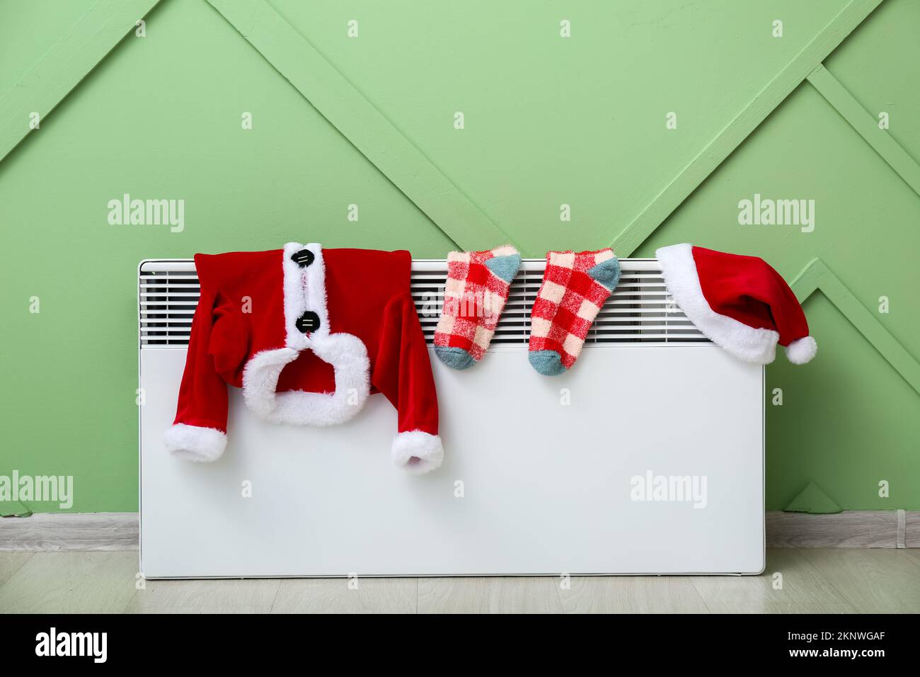Baby Santa costume, socks and hat drying on electric radiator near ...