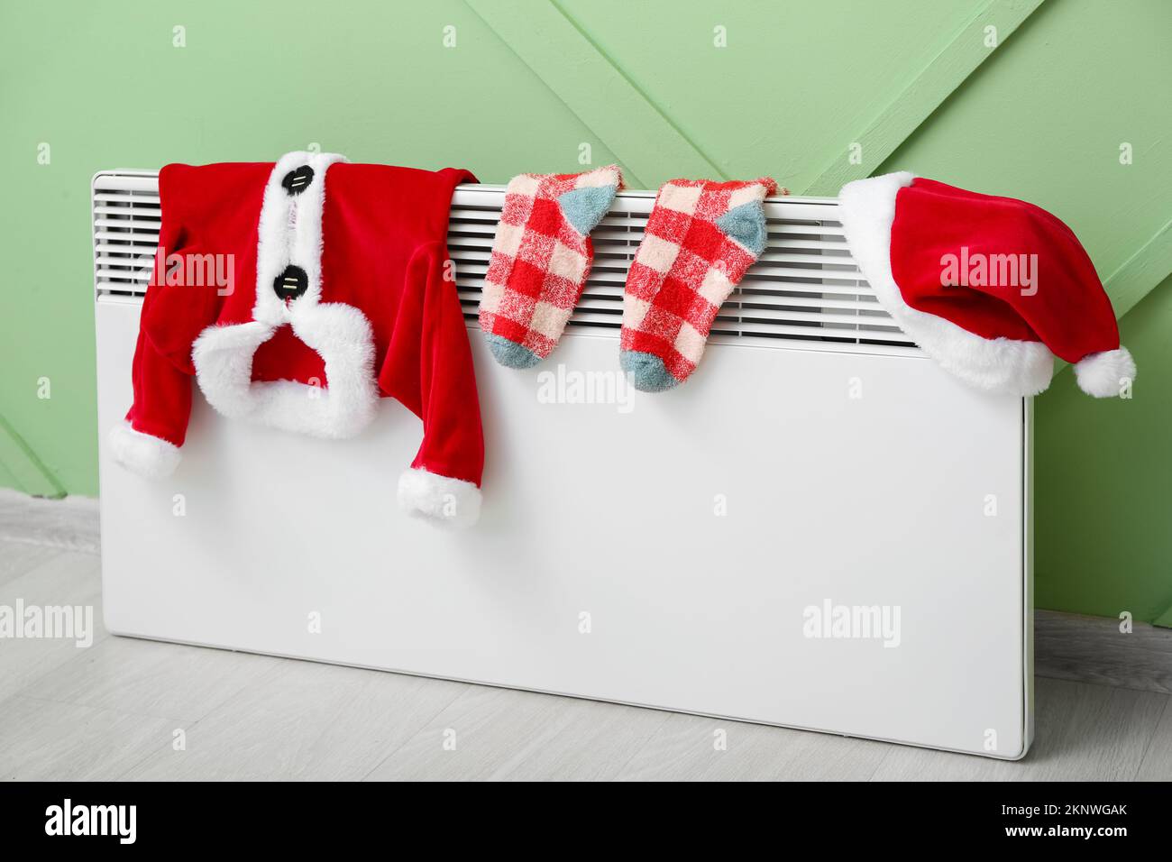 Baby Santa costume, socks and hat drying on electric radiator near ...