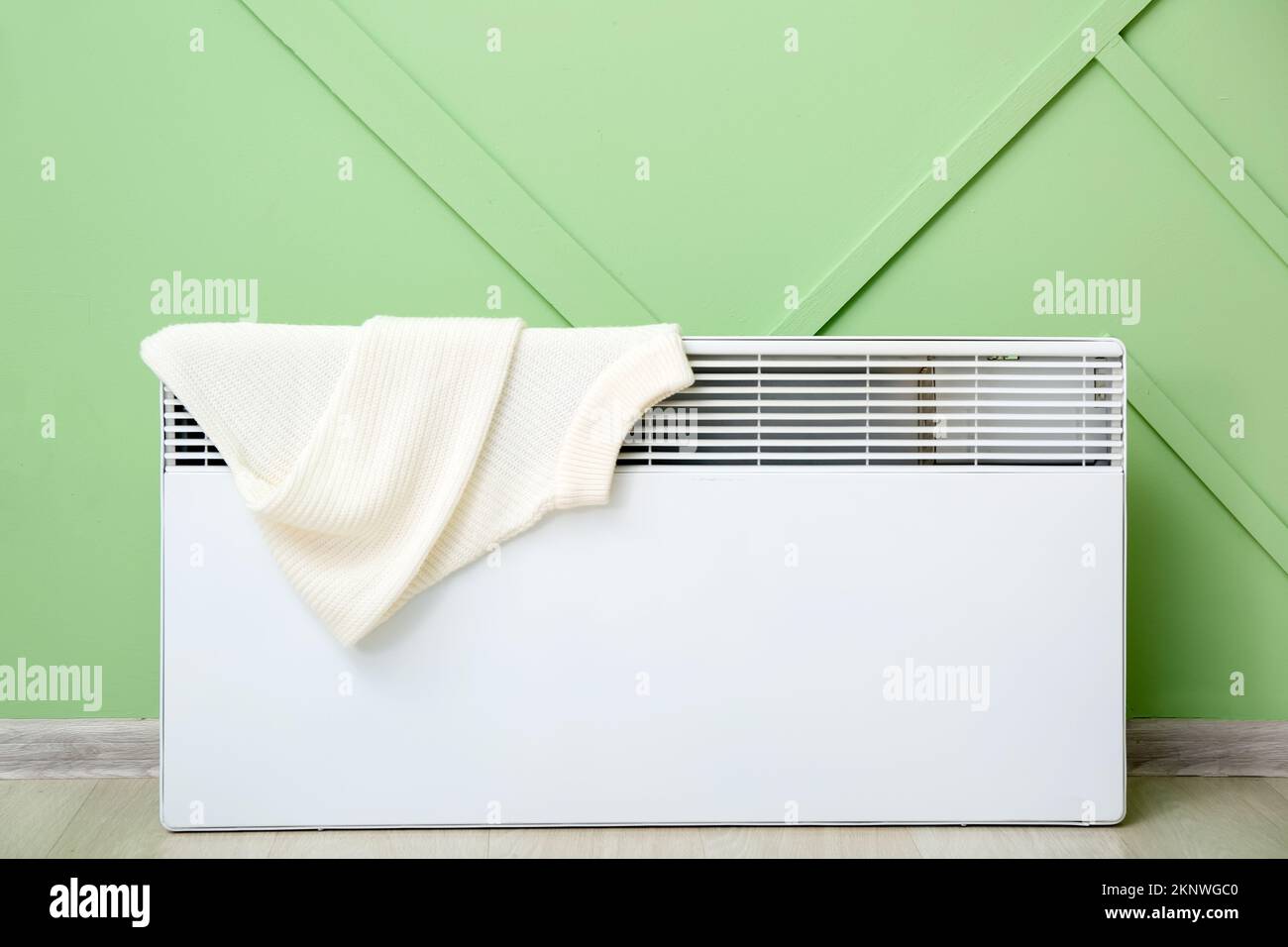 Warm sweater drying on electric radiator near green wall Stock Photo ...
