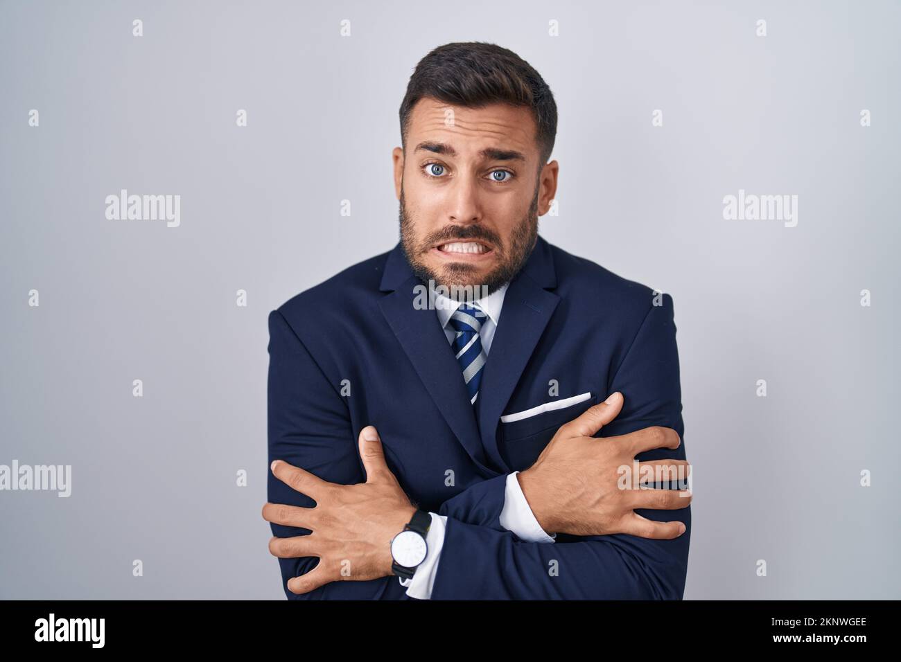 Handsome hispanic man wearing suit and tie shaking and freezing for ...