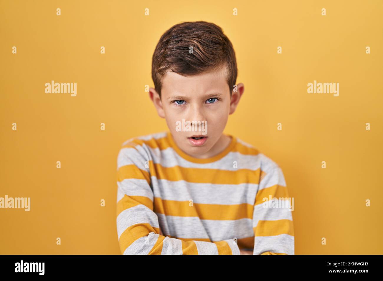Young caucasian kid standing over yellow background skeptic and nervous ...