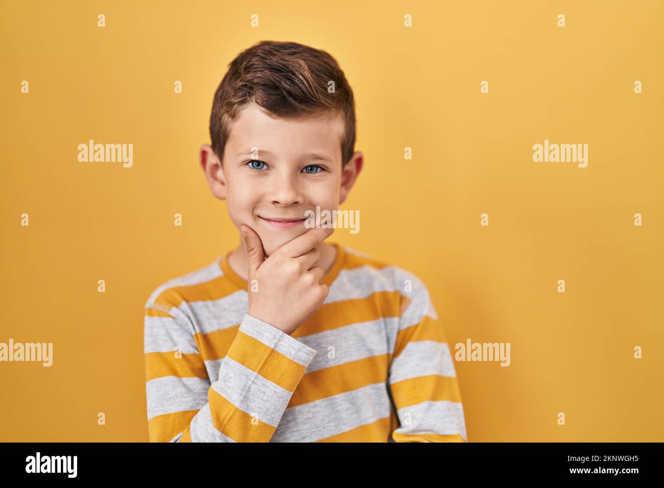 Young caucasian kid standing over yellow background looking confident ...