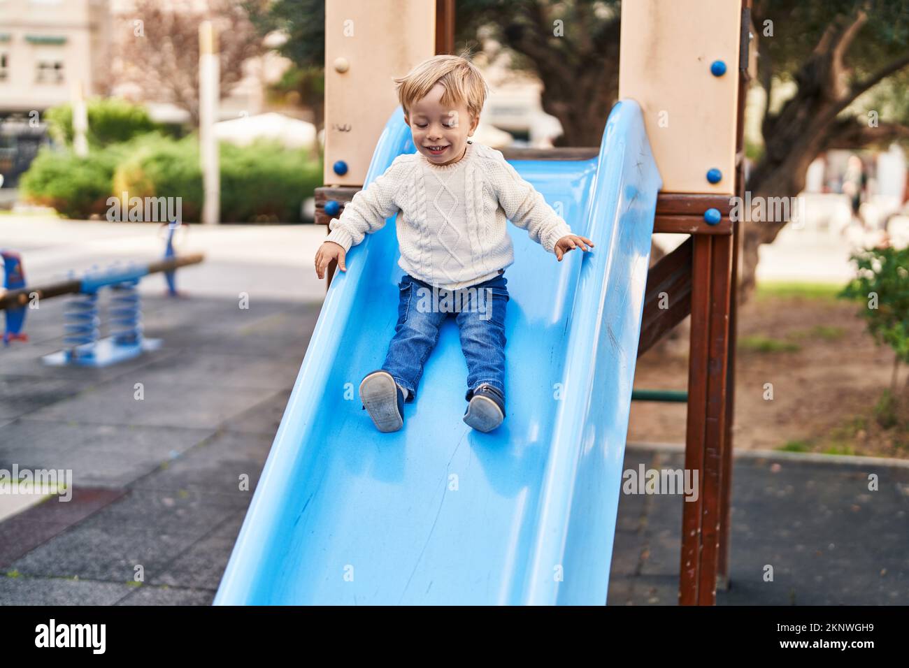 Adorable toddler playing on slide at park Stock Photo - Alamy