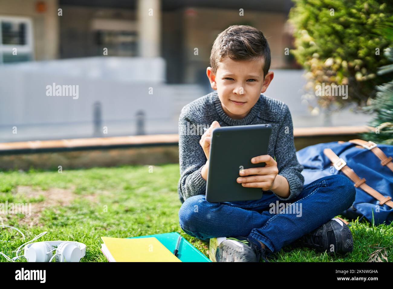 Blond child using touchpad sitting on grass at park Stock Photo - Alamy