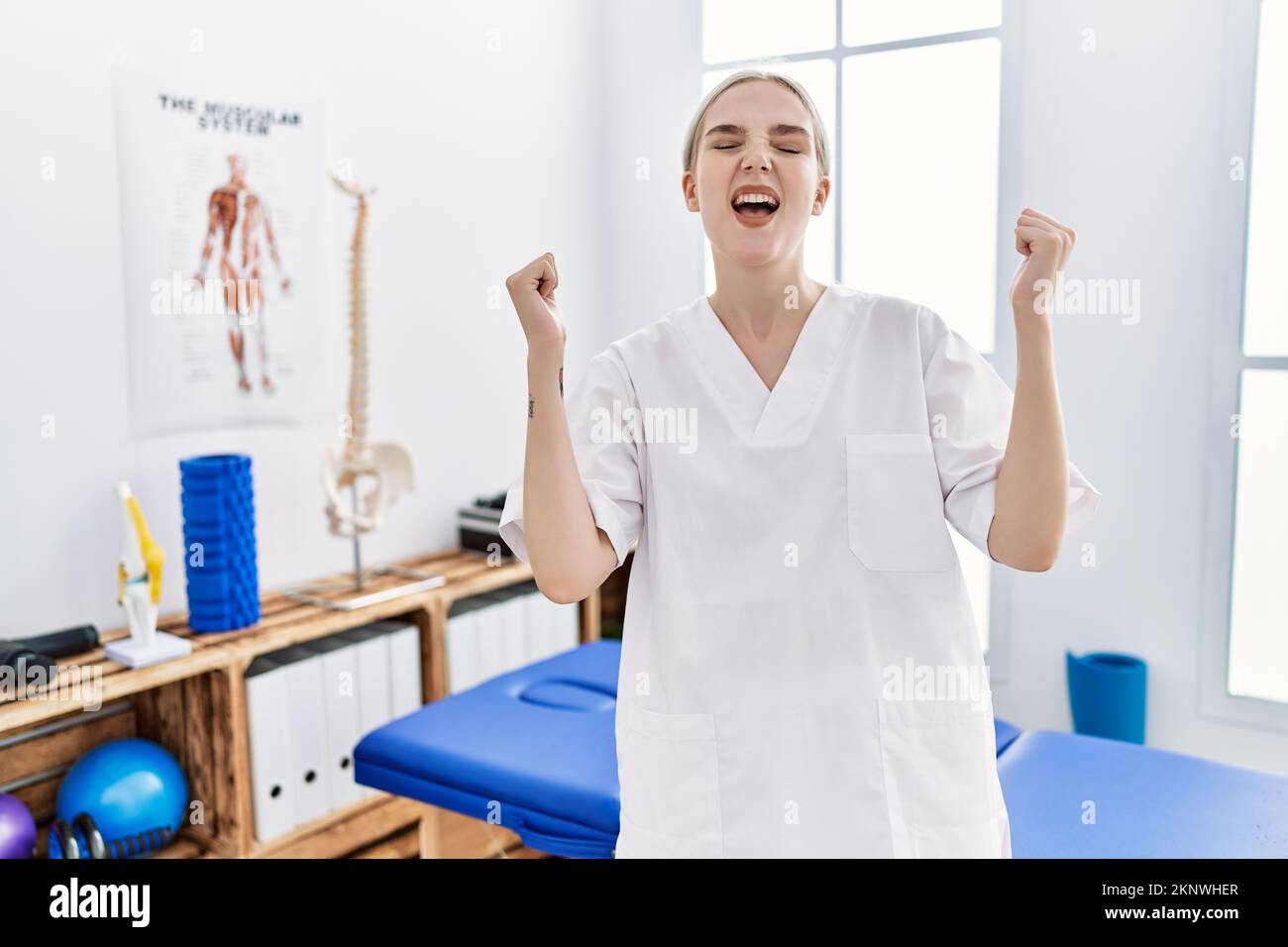 Young caucasian woman working at pain recovery clinic celebrating ...