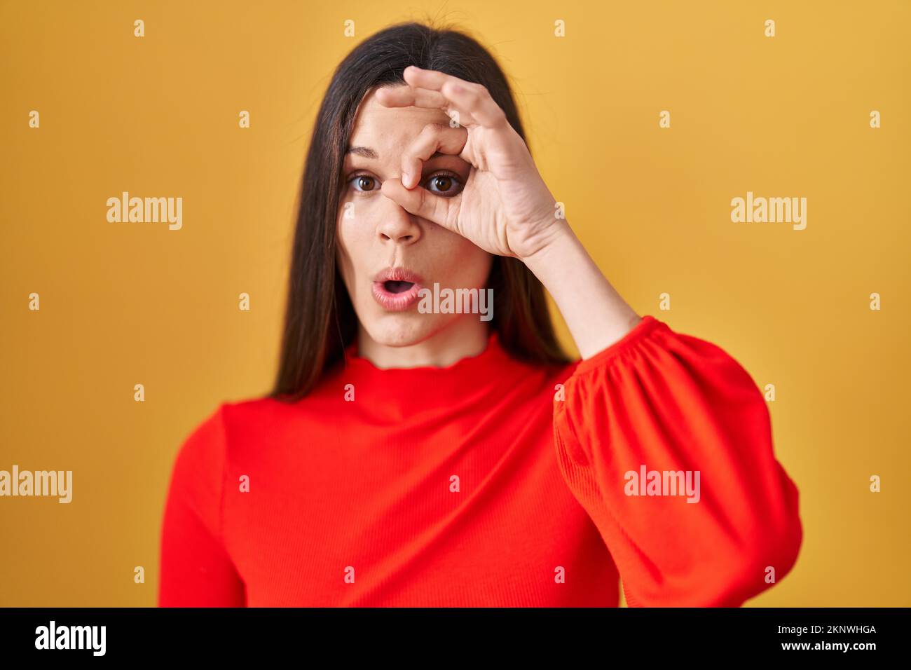 Young hispanic woman standing over yellow background doing ok gesture ...