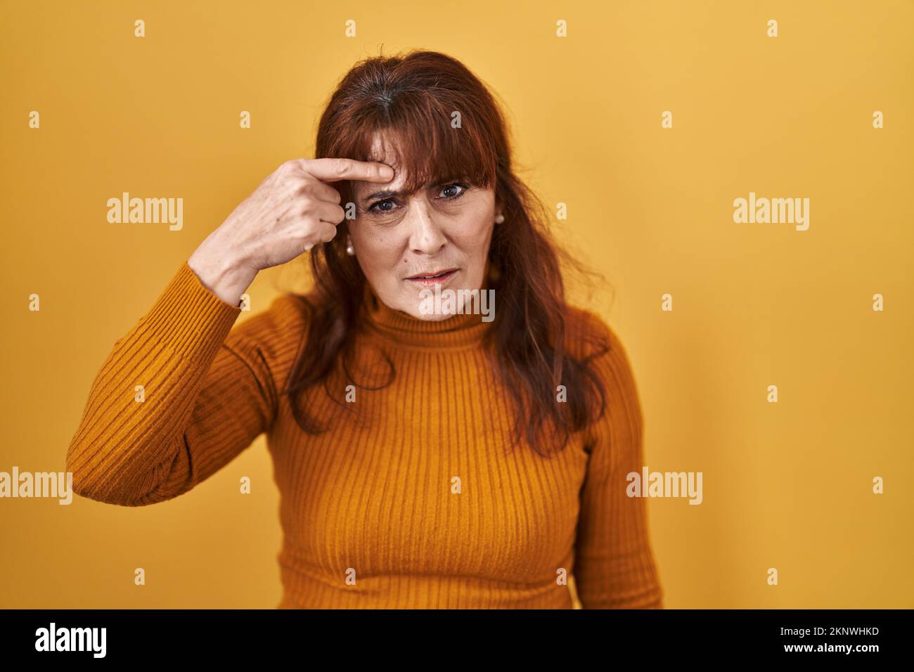 Middle age hispanic woman standing over yellow background pointing ...