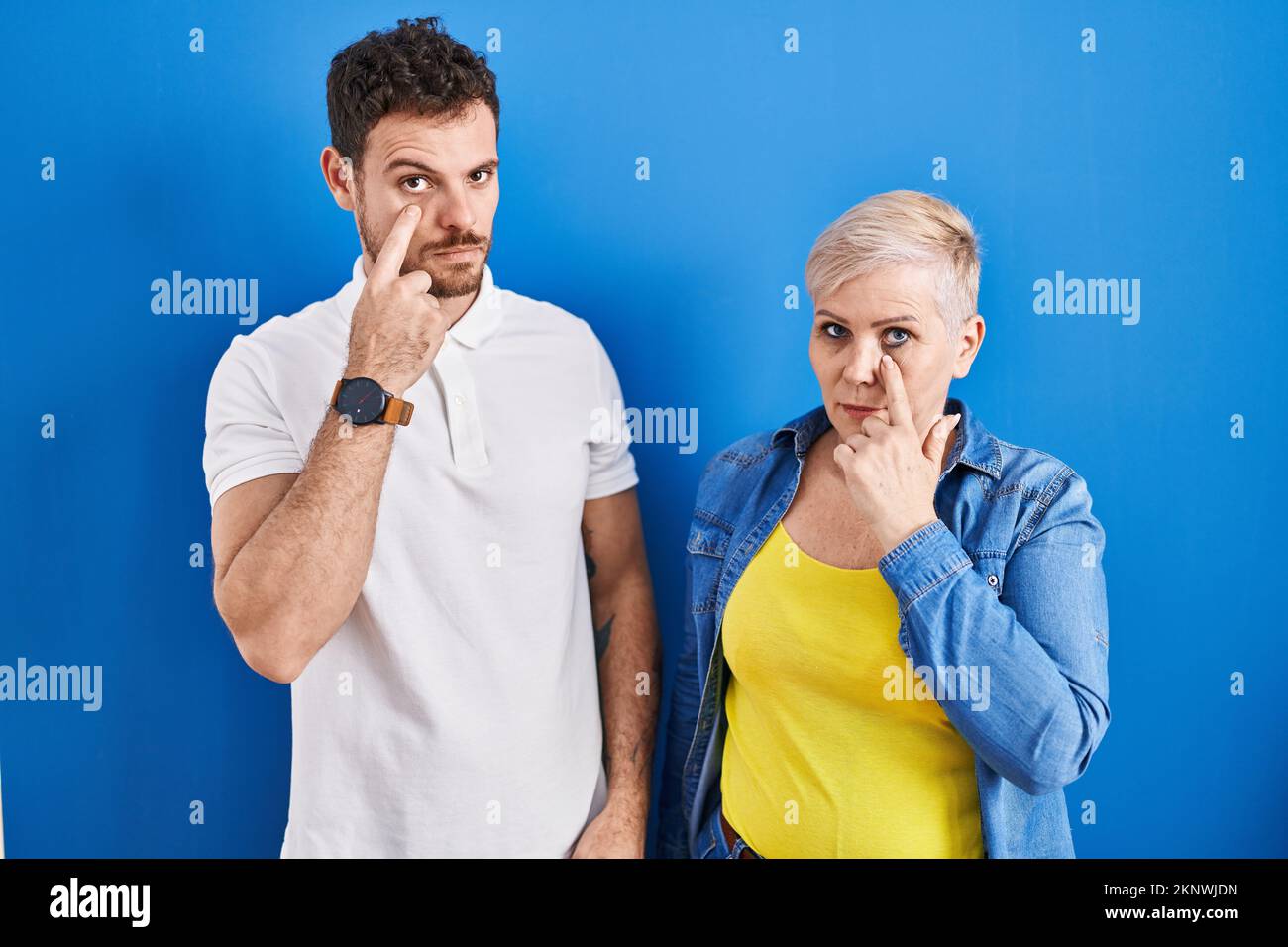 Young brazilian mother and son standing over blue background pointing ...